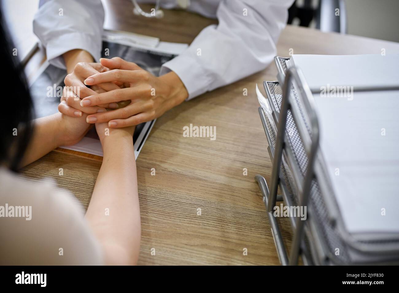 A cheerful female doctor holding a patient's hands to reassuring during ...