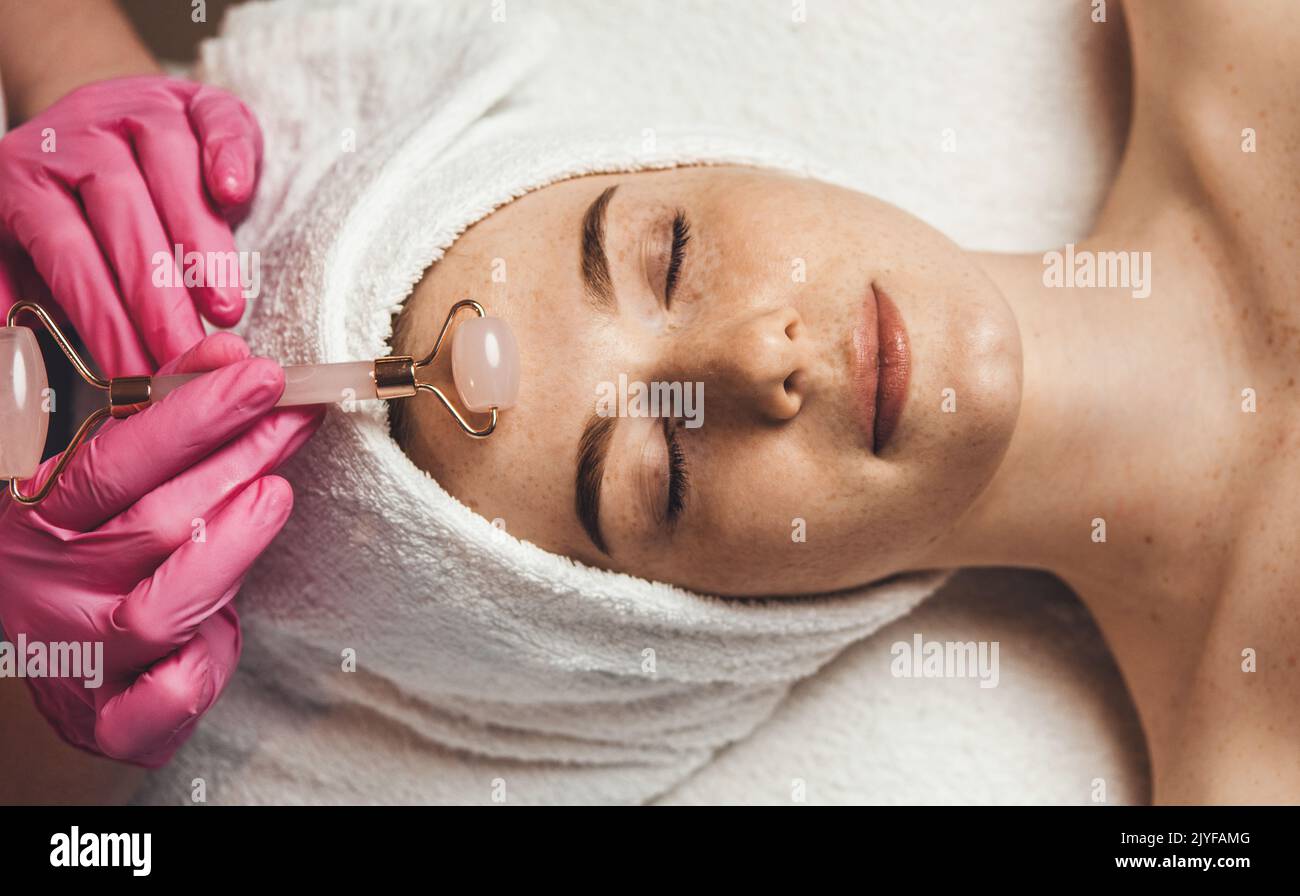 Top view of a caucasian woman getting massage with jade face roller in ...