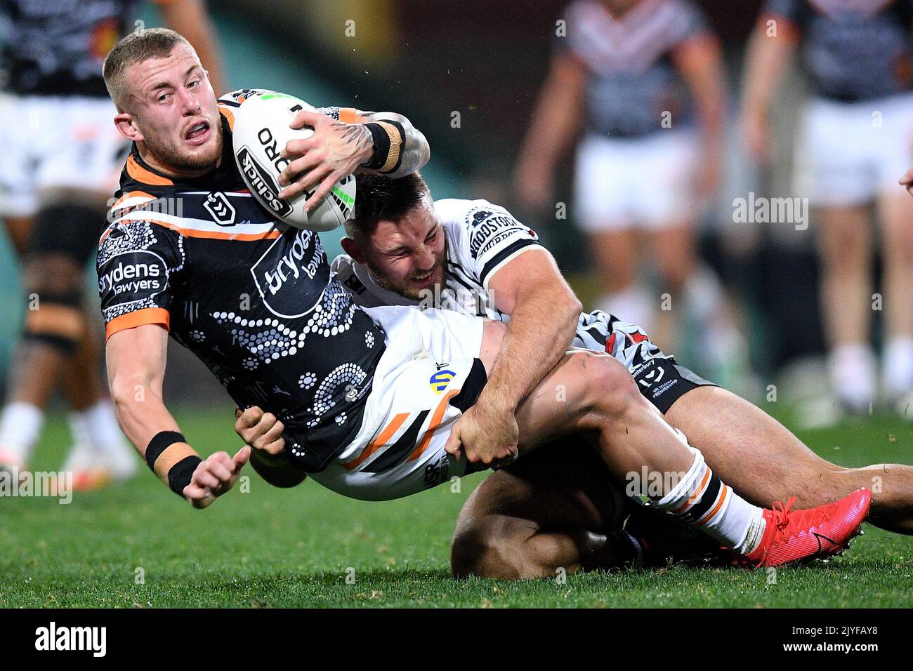 Sam McIntyre of the Tigers is tackled by Karl Lawton of the Warriors ...