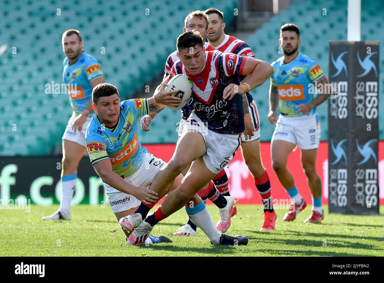Joseph Manu of the Roosters is tackled by Ashley Taylor of the Titans ...
