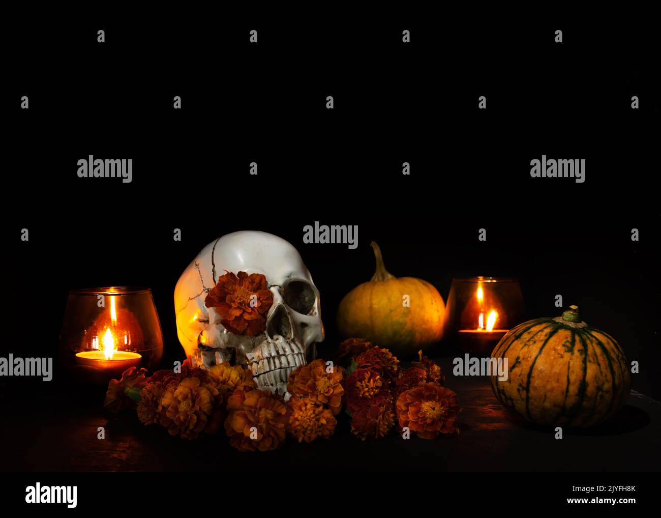 Skull, Burning candles and orange marigold flowers on black background ...