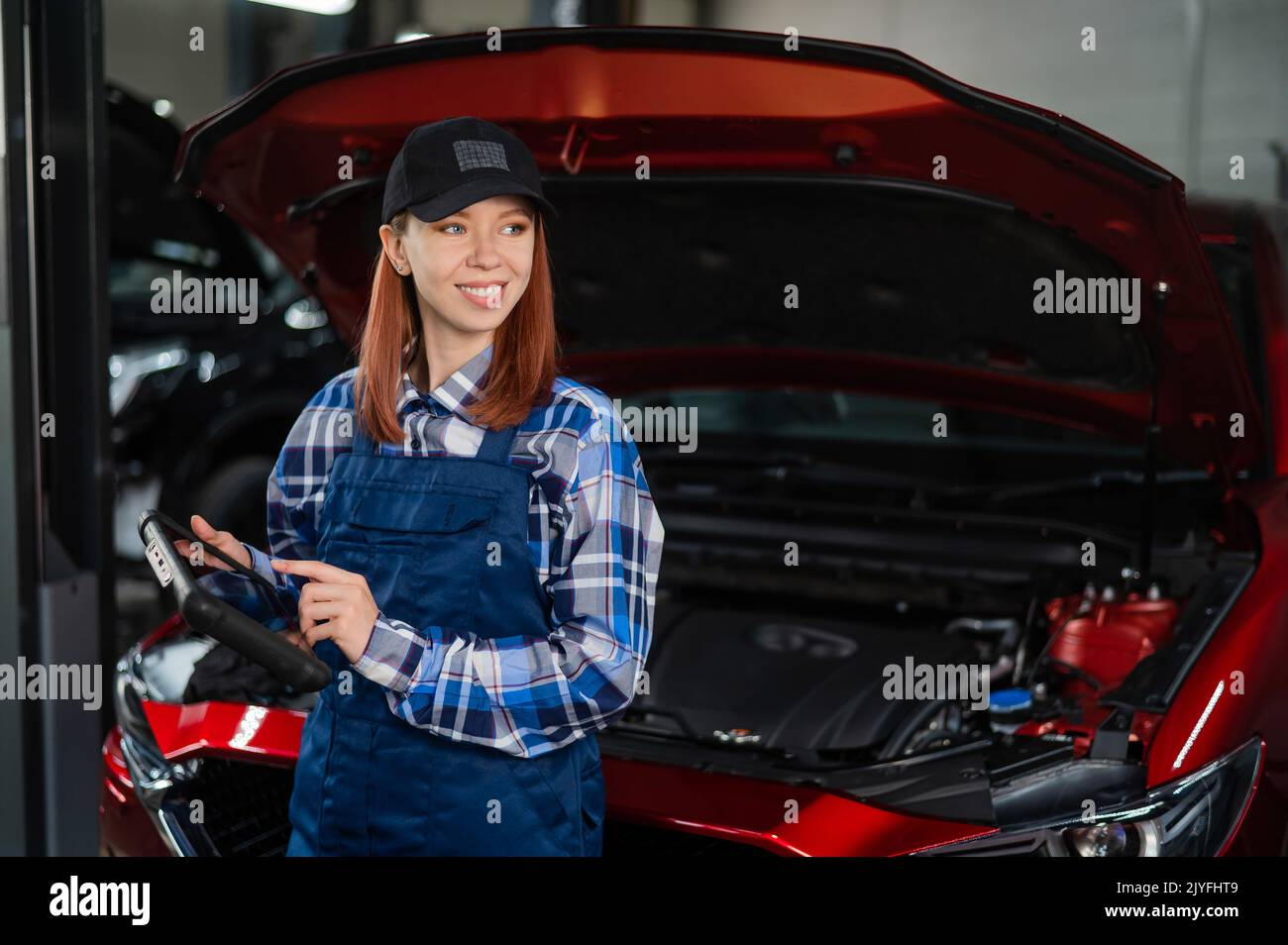 Caucasian female auto mechanic uses a special computer to diagnose ...