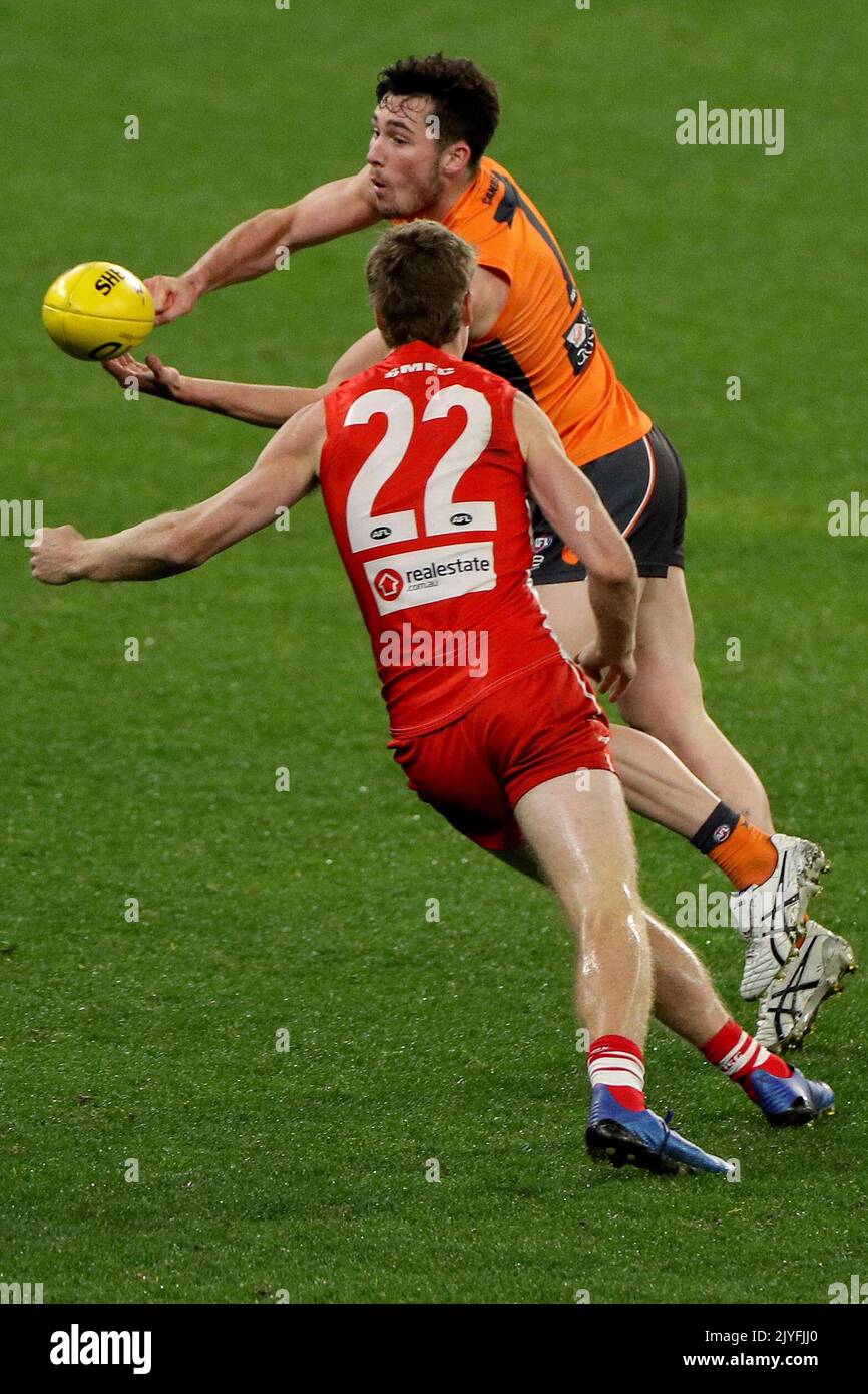 Lachlan Ash of the Giants handballs past Nick Blakey of the Swans ...