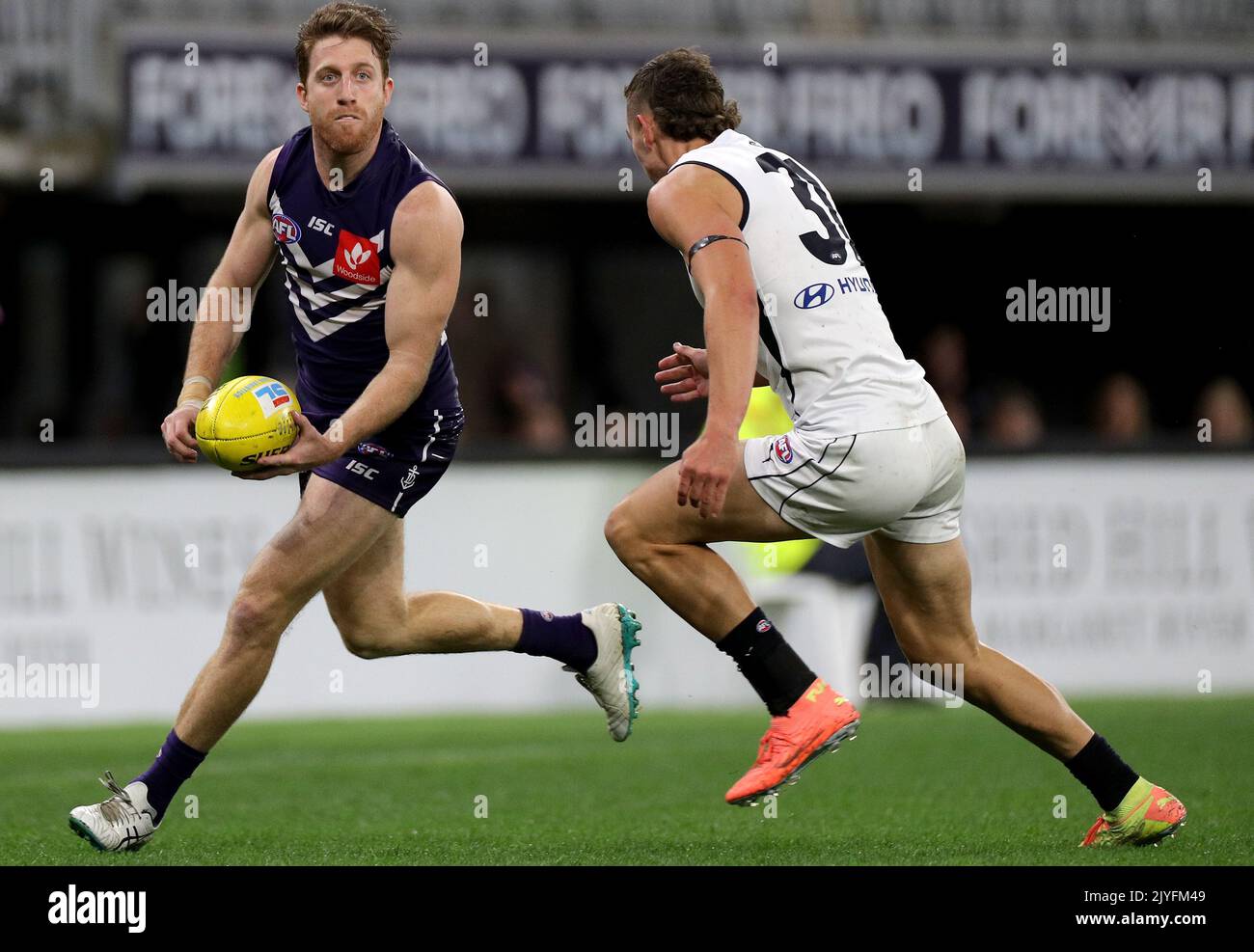 Reece Conca of the Dockers handballs under pressure from Tom Williamson ...