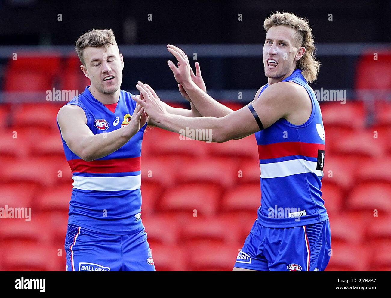 Aaron Naughton of the Bulldogs (right) reacts after kicking a goal ...