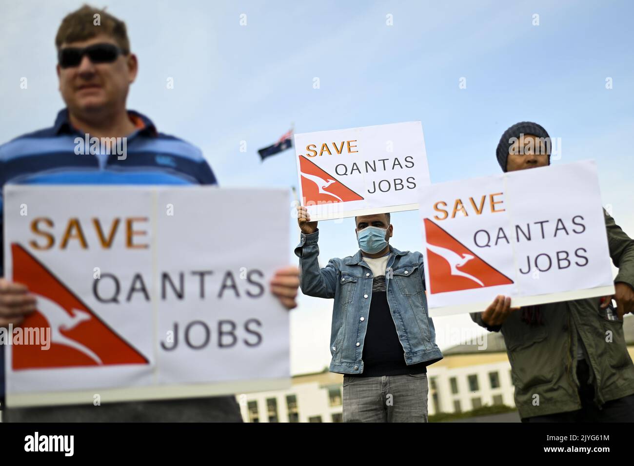 Qantas employees hold signs during a rally organised by the Transport ...