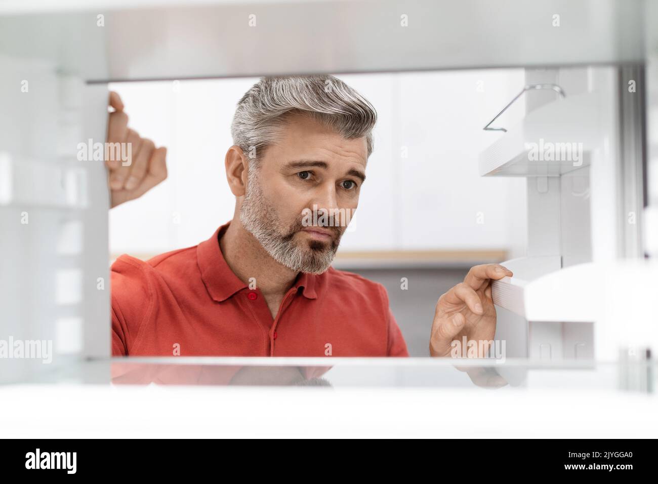 Upset middle aged man looking inside empty fridge Stock Photo - Alamy