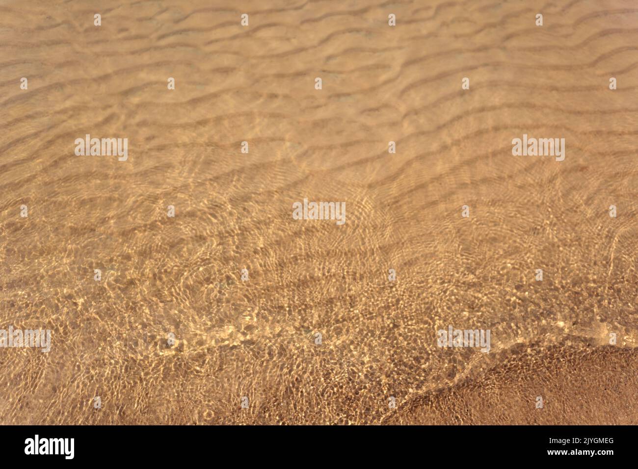 Water rippling over the shore line of a sandy beach Stock Photo - Alamy