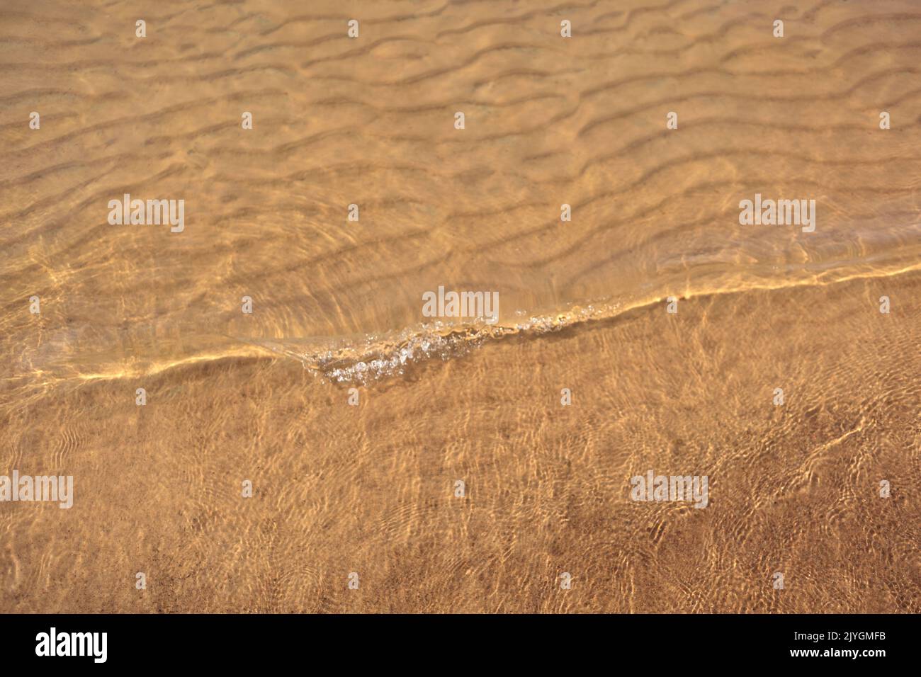 Water rippling over the shore line of a sandy beach Stock Photo - Alamy