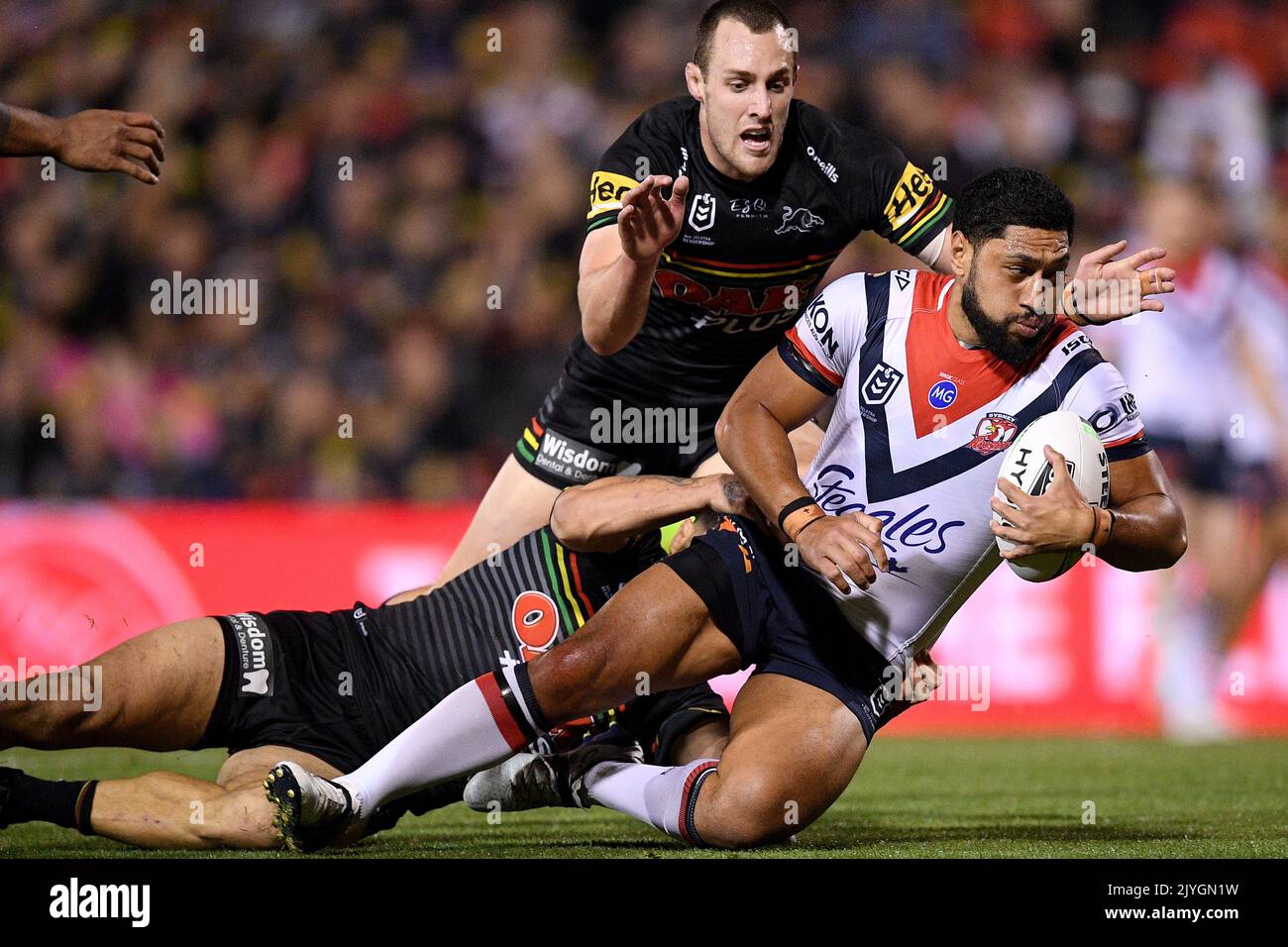 Isaac Liu of the Roosters is tackled by James Tamou (left) and Issah ...