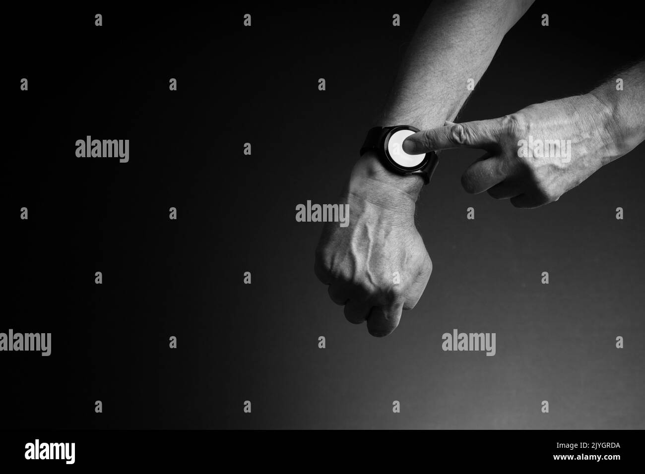 Black and white image of man's hand with finger pressing smart watch on ...