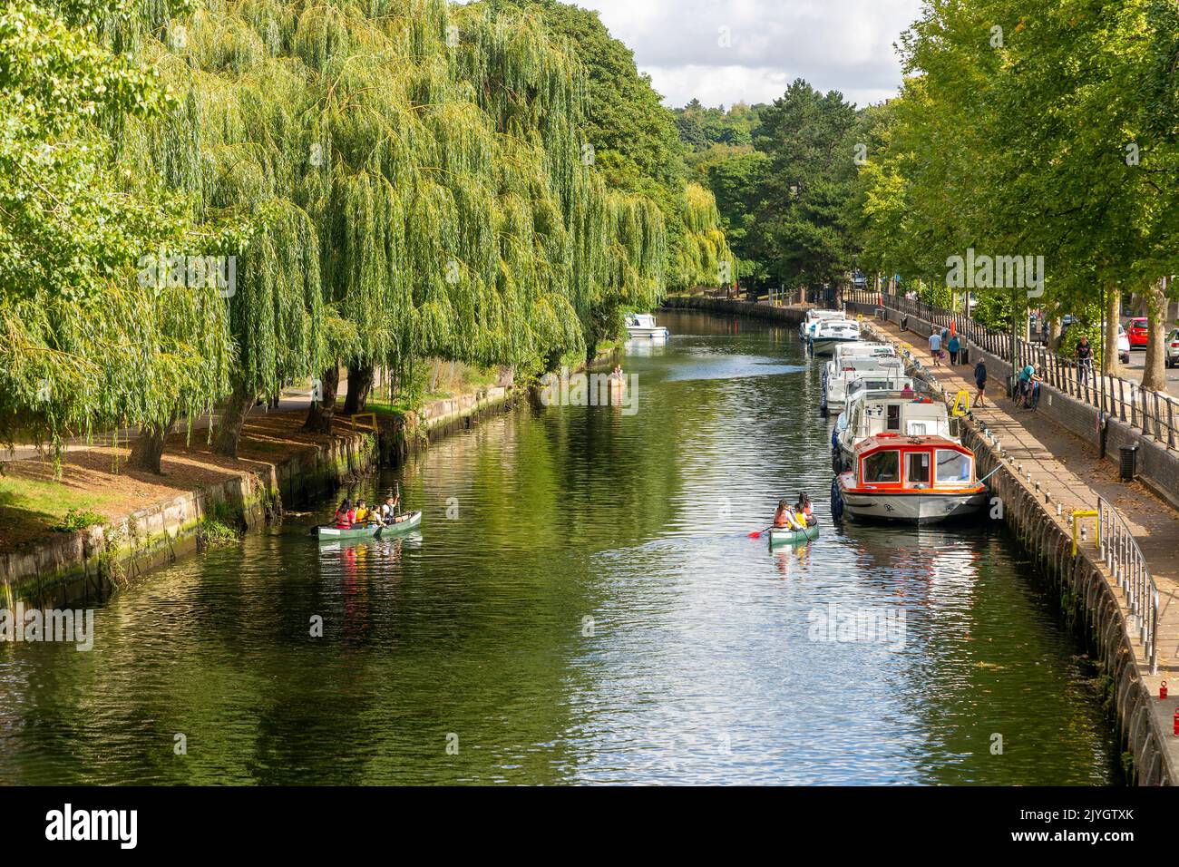 Boats moored children kayaking, River Wensum, Norwich, Norfolk, England ...