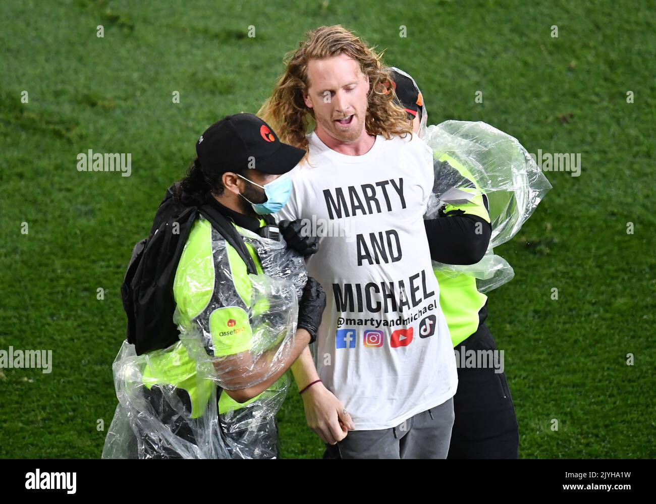 A pitch invader (centre) is seen being carried off the field by ...