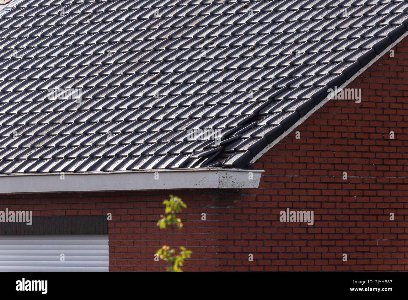A portrait of a destroyed black tile roof of a house. The building got ...