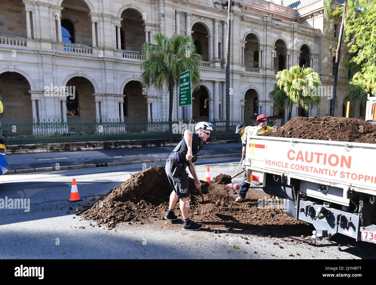 Police are seen cleaning up a dumped pile of manure which had been ...