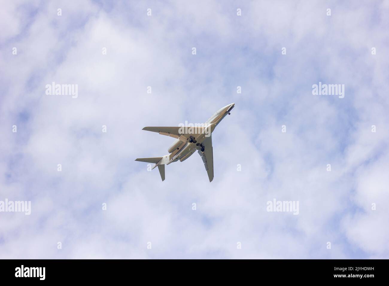 A portrait of a private plane flying low in a cloudy sky. The jet plane ...
