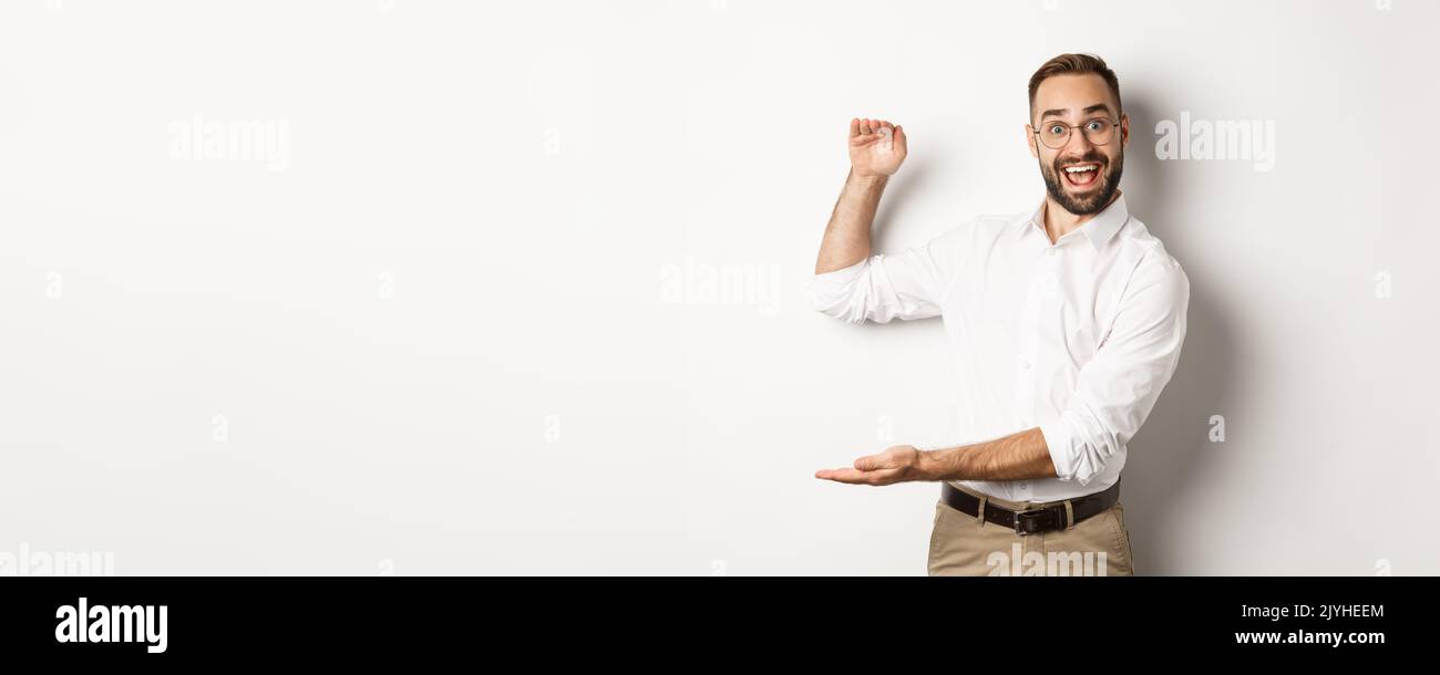 Amazed businessman showing big object, describe something large and ...