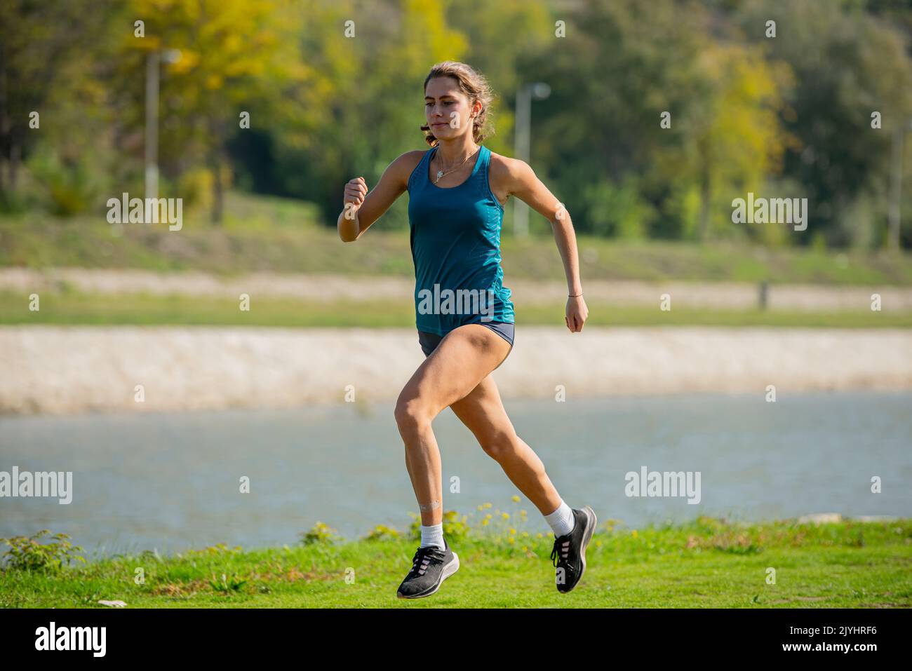 Attractive and beautiufl fit girl is running all alone by the river ...