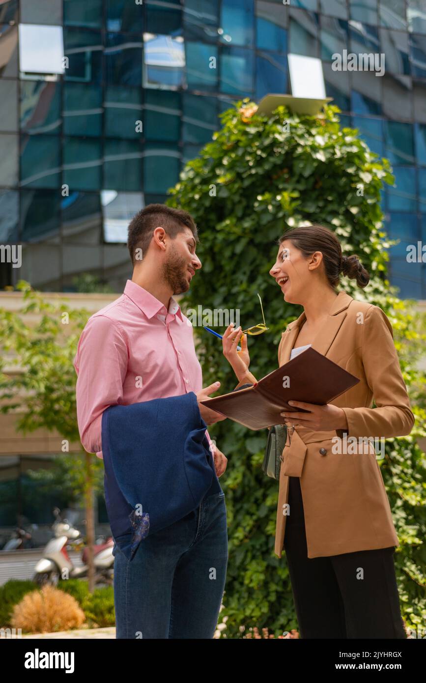 A young businessman is trying to be serious while his female colleague ...