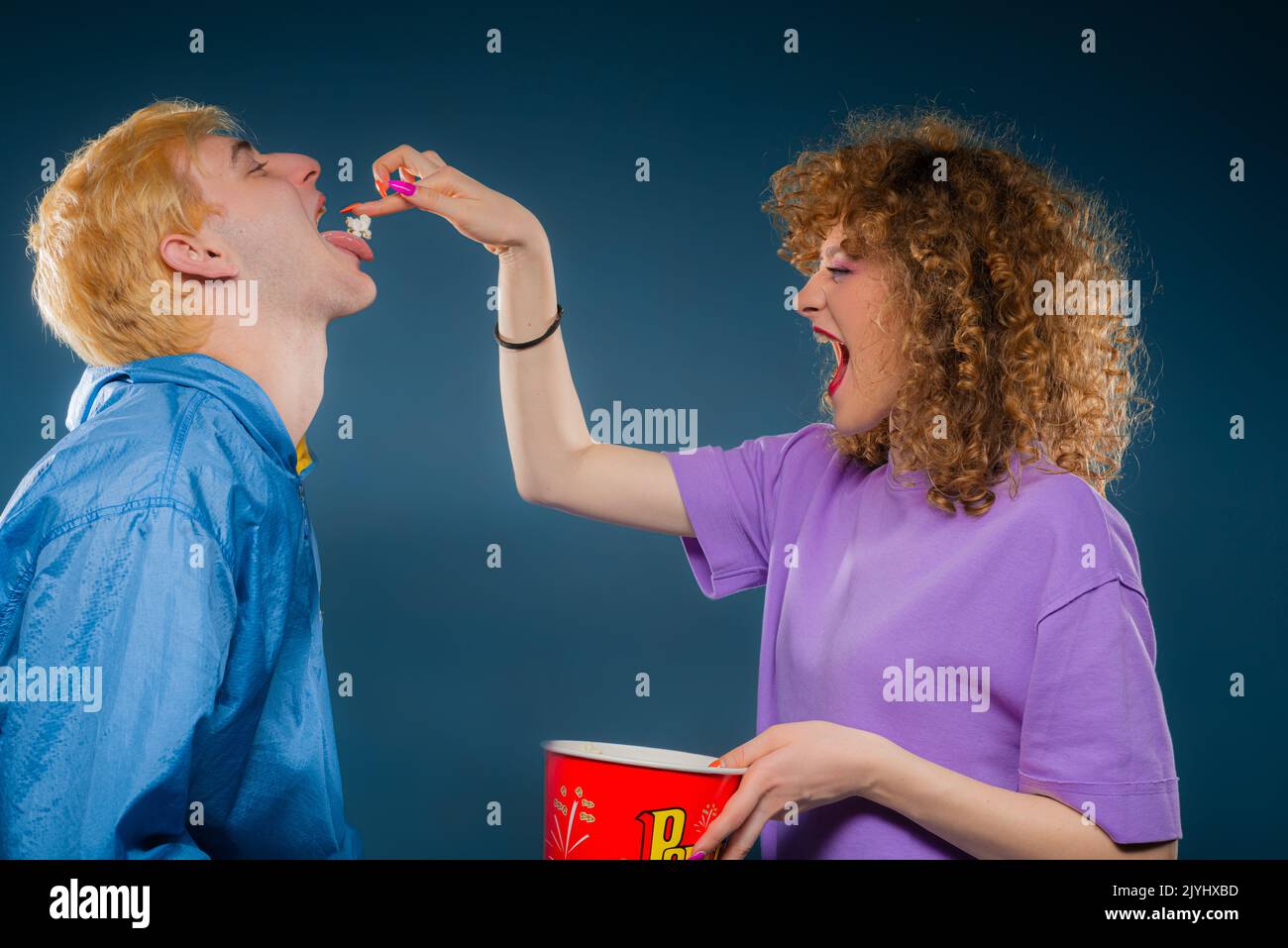 Cute and attractive couple is giving popcorn to each other while having ...
