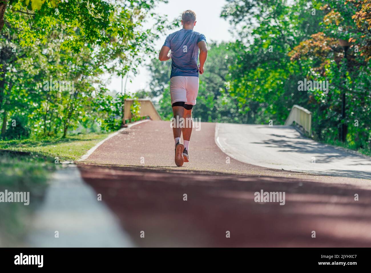 Athletic young man running on the race track in a sports park Stock ...