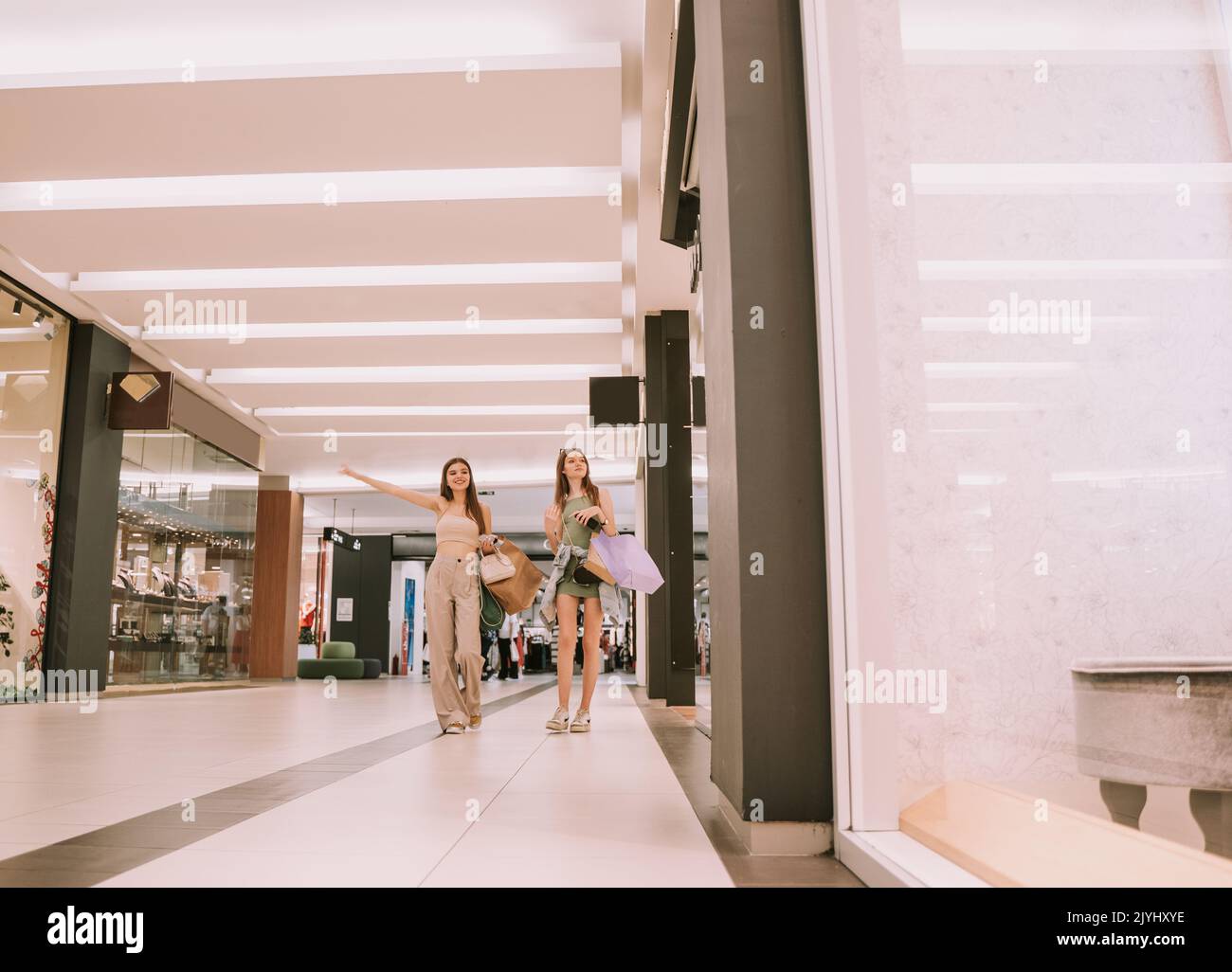 Pretty girls walking at the mall while looking at the shop windows ...