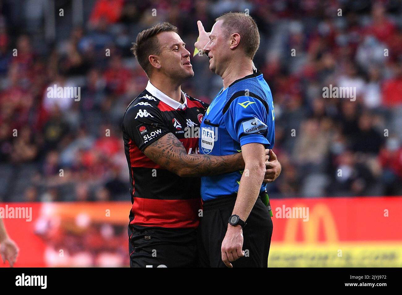 Simon Cox of the Wanderers embraces referee Kurt Ams after being shown ...