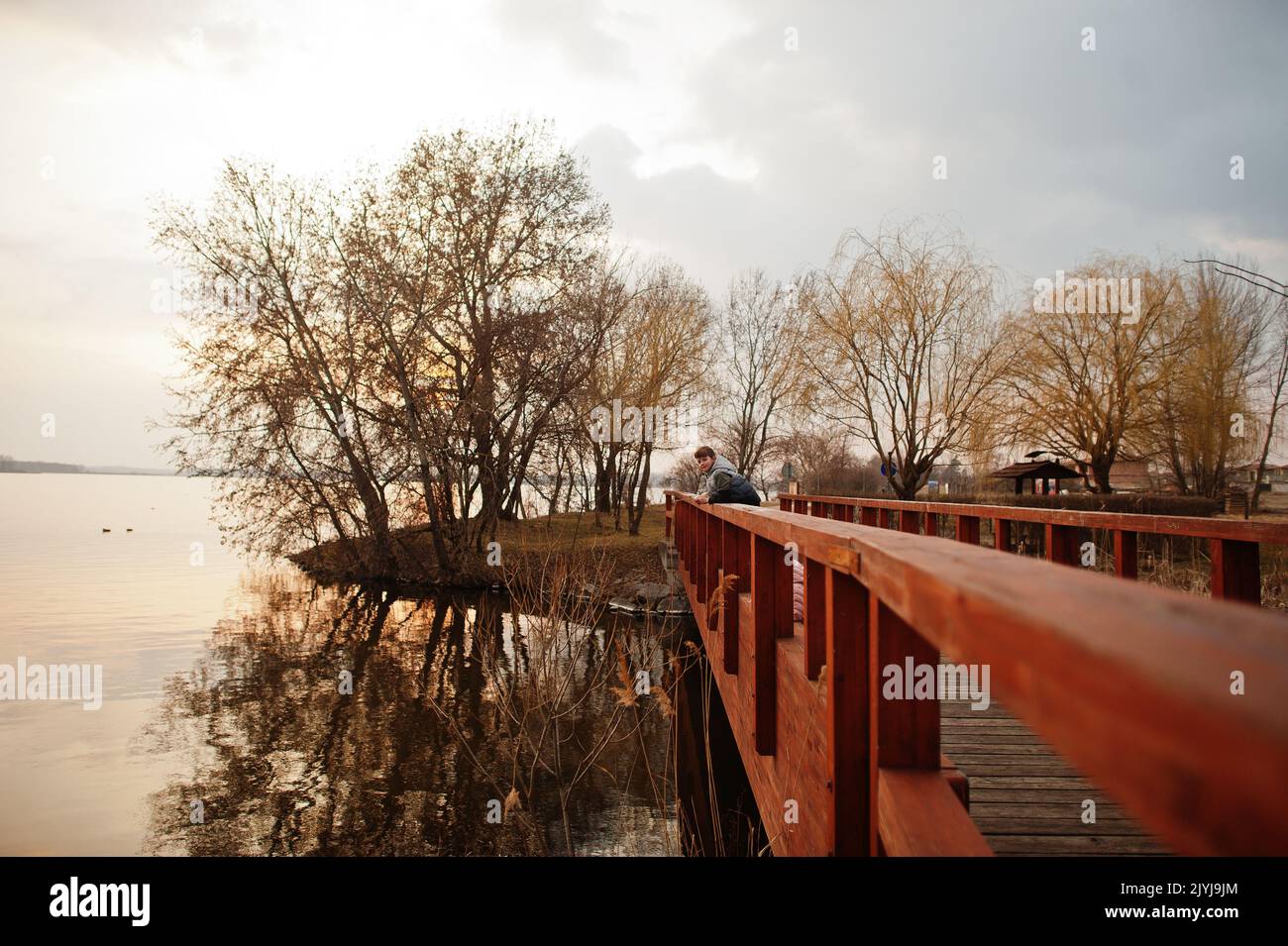 Boy looking in wooden bridge of island at lake Stock Photo - Alamy