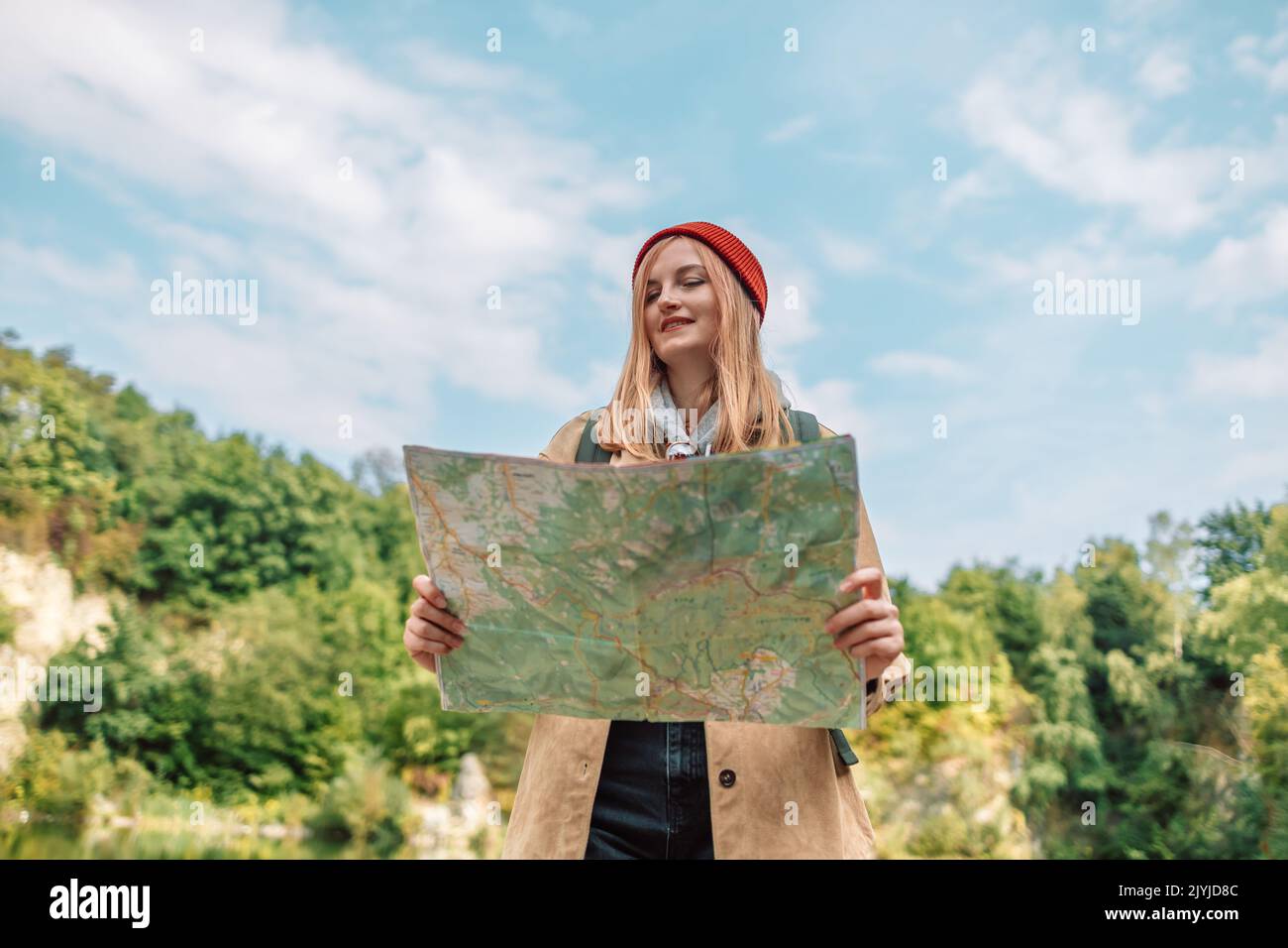 Happy blonde woman holding and looking at the paper topographic map ...