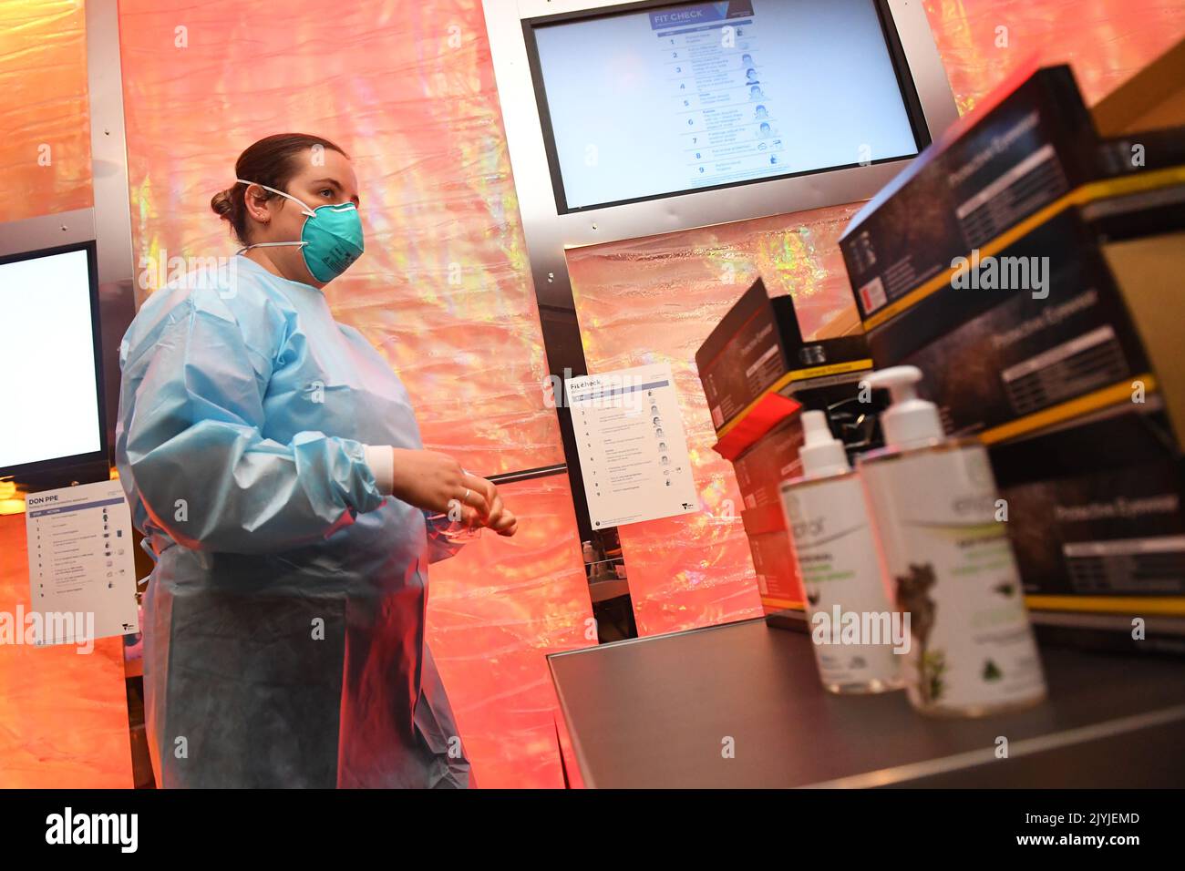 A Healthcare worker is seen at a personal protective equipment station ...