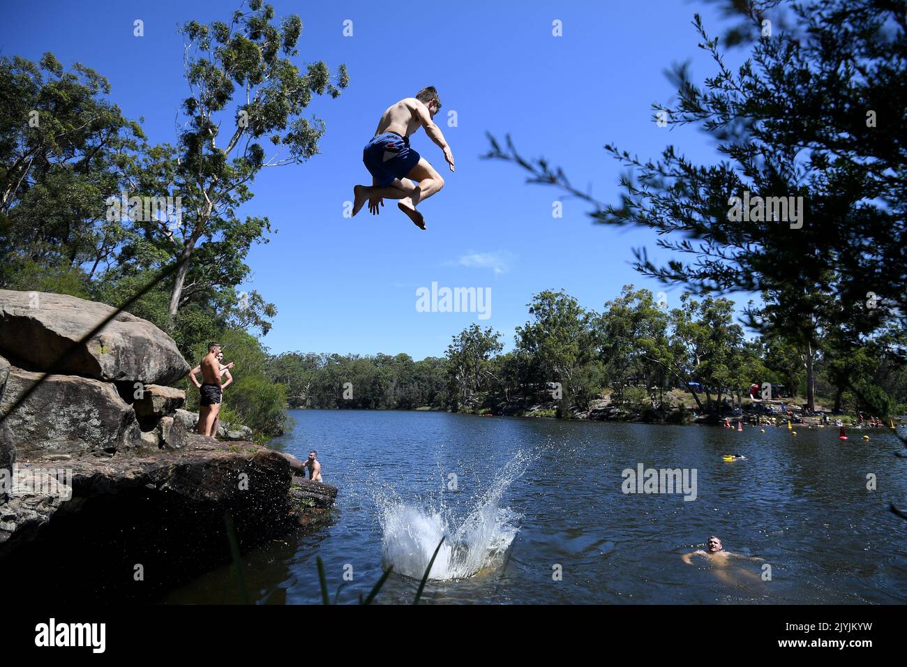 Swimmers are seen jumping off a rock at Lake Parramatta, in Parramatta, west of Sydney, Saturday ...