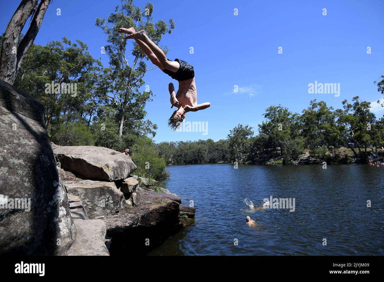 Swimmers are seen jumping off a rock at Lake Parramatta, in Parramatta ...