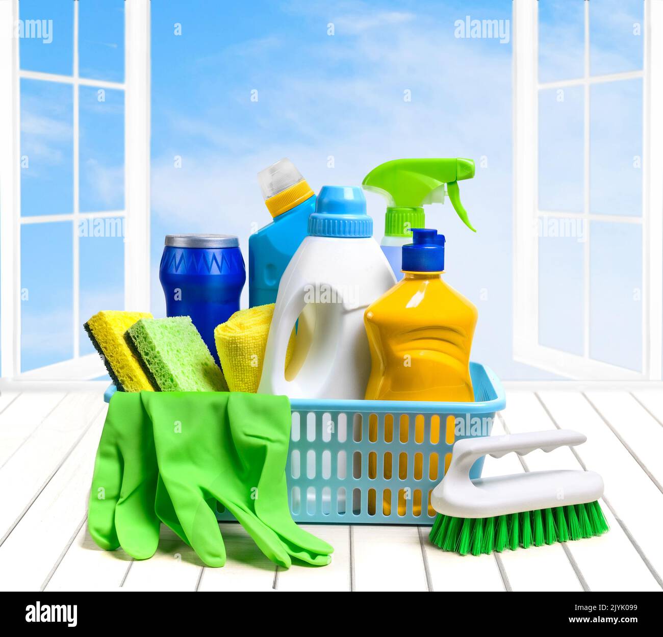 Household cleaning supplies in plastic basket on the white table over ...
