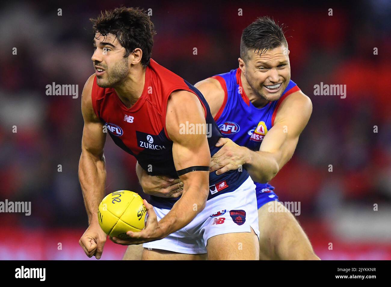 Christian Petracca (left) of Melbourne Demons give off a handball ...