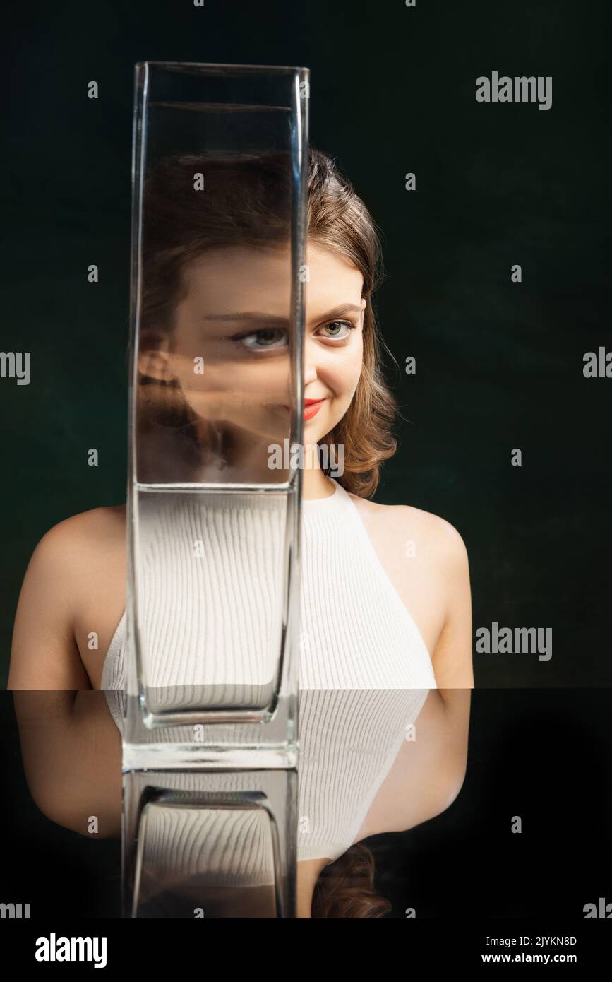 Surreal art photography. Young girl's face through glass vase over dark ...