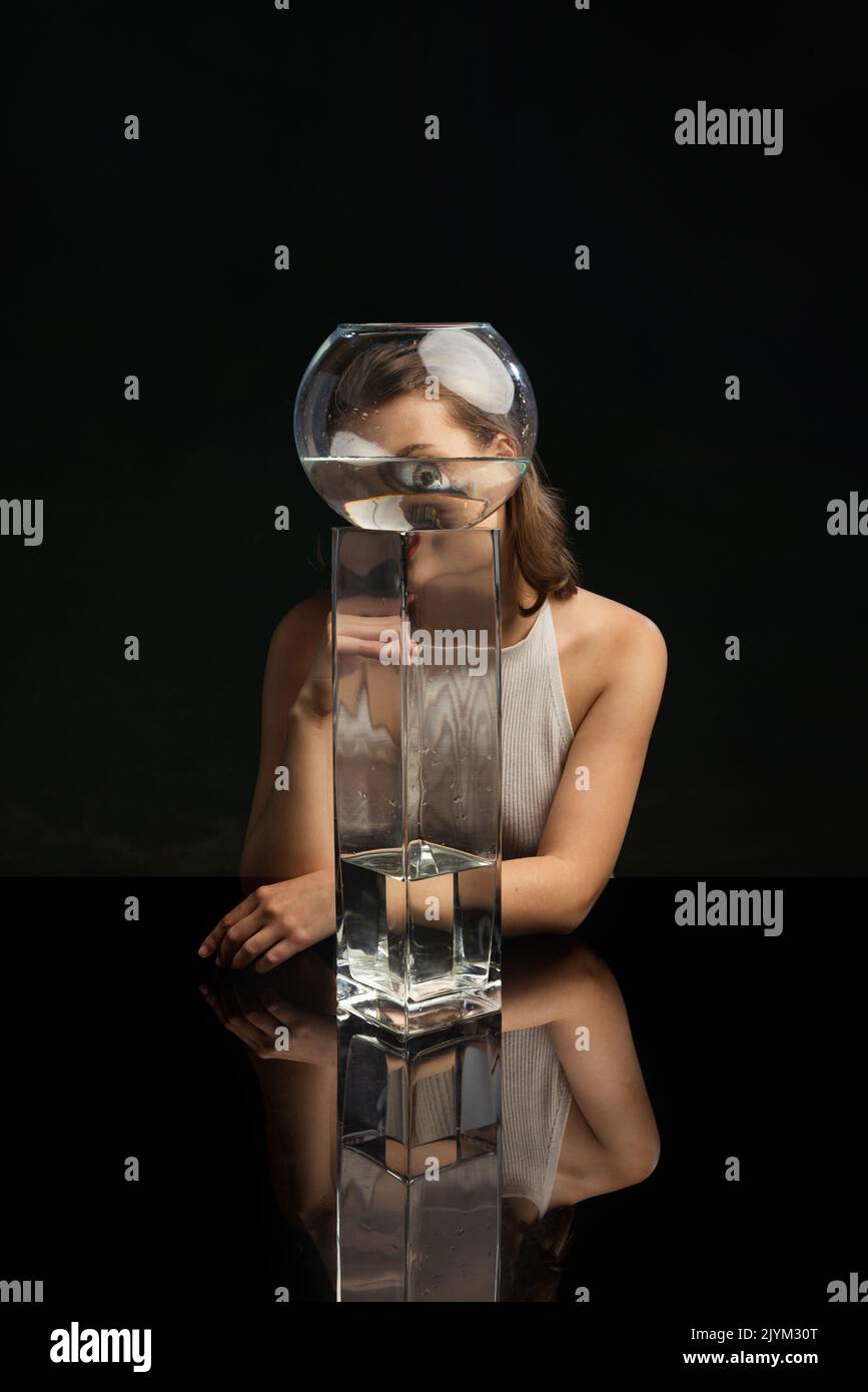 Creative composition with young girl sitting behind glass vases and ...