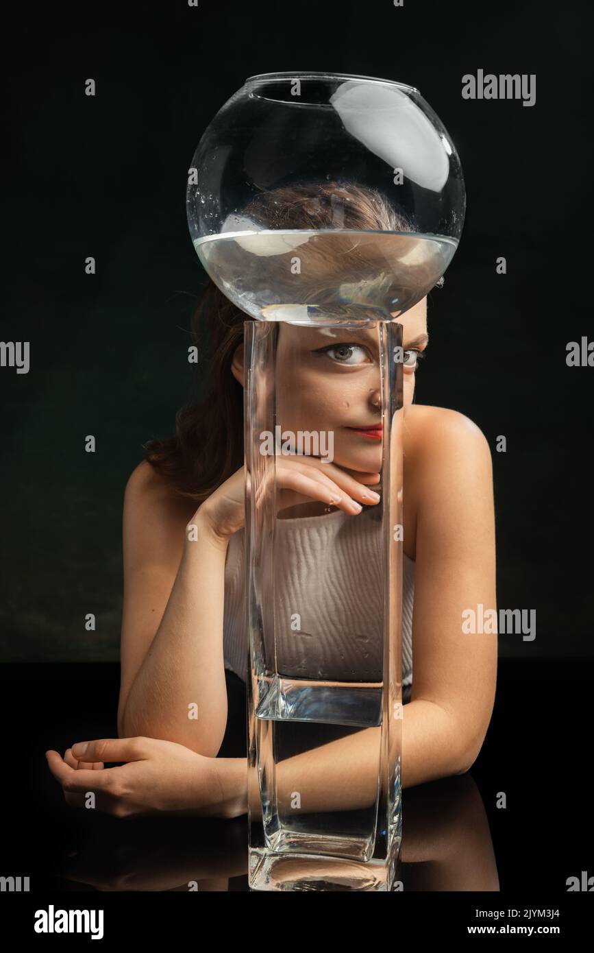 Creative composition with young girl sitting behind glass vases and ...