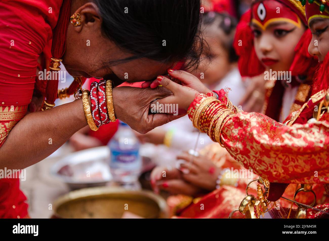 A woman offers prayers to the hand of a child who is dressed as the ...