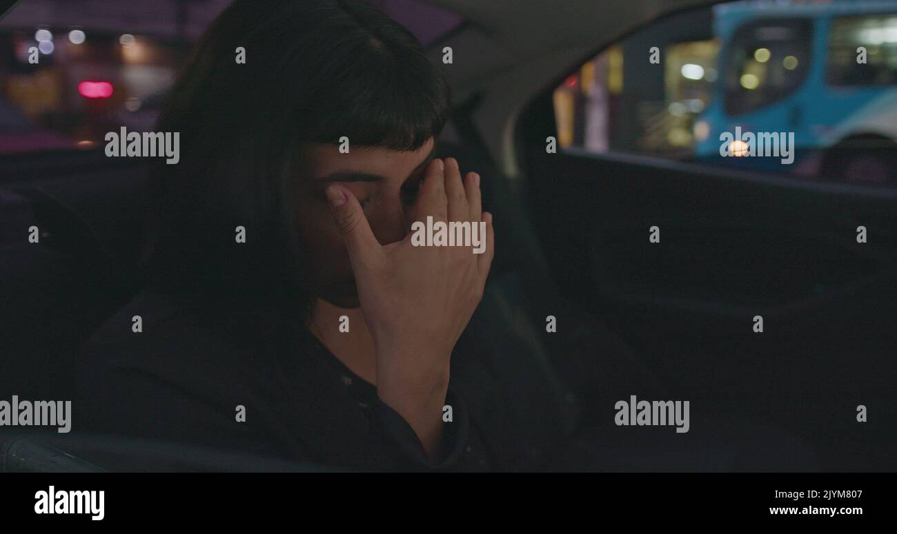 Young woman in car backseat stuck in traffic at night commuting from ...