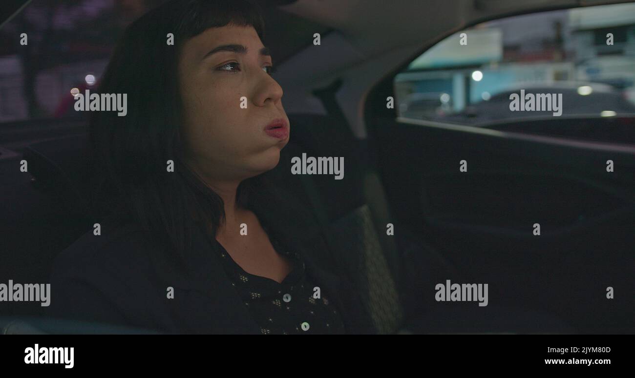 Young woman in car backseat stuck in traffic at night commuting from ...