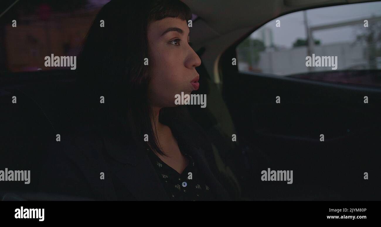 Young woman in car backseat stuck in traffic at night commuting from ...