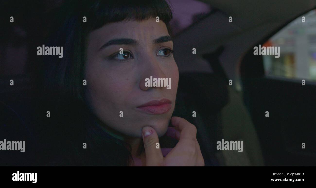 Young woman in car backseat stuck in traffic at night commuting from ...