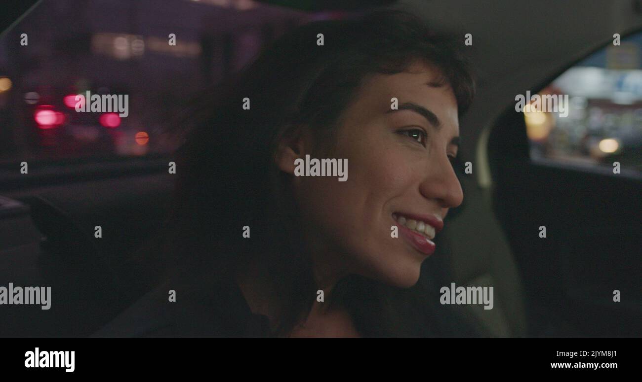 Happy female passenger in backseat of car smiling while looking out ...