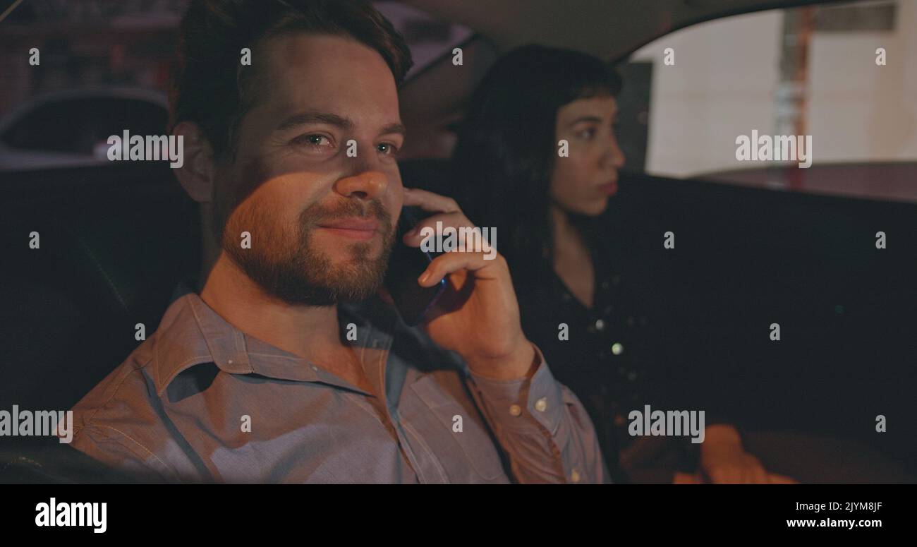 People riding taxi cab in car backseat at night. Young man and woman ...