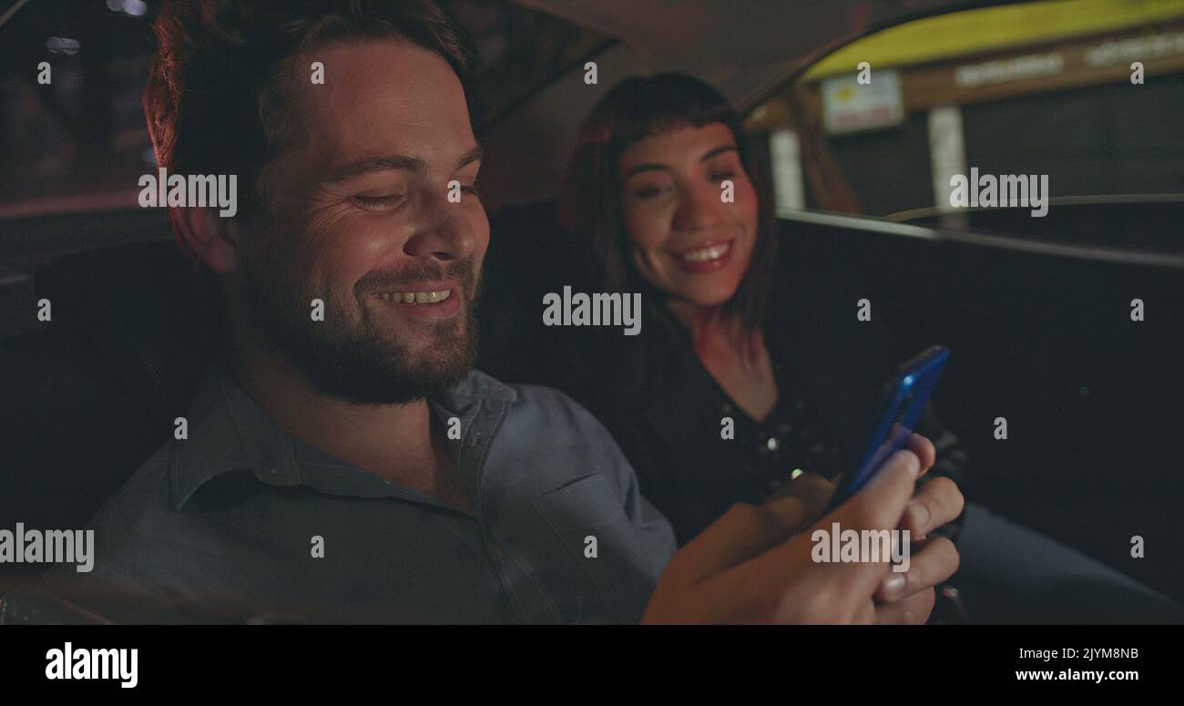 People riding taxi cab in car backseat at night. Young man and woman ...