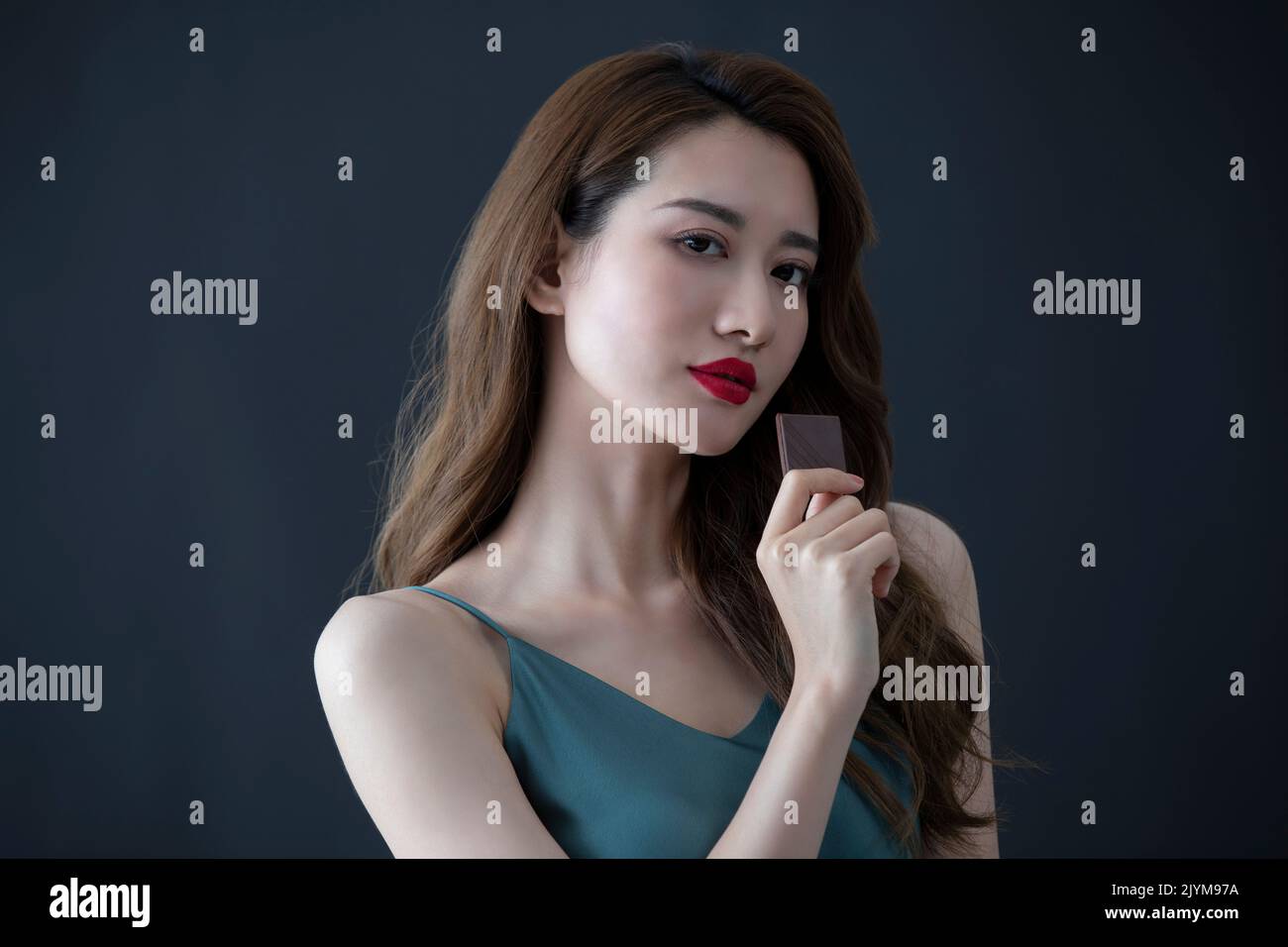 Beautiful young Chinese woman eating chocolate Stock Photo - Alamy