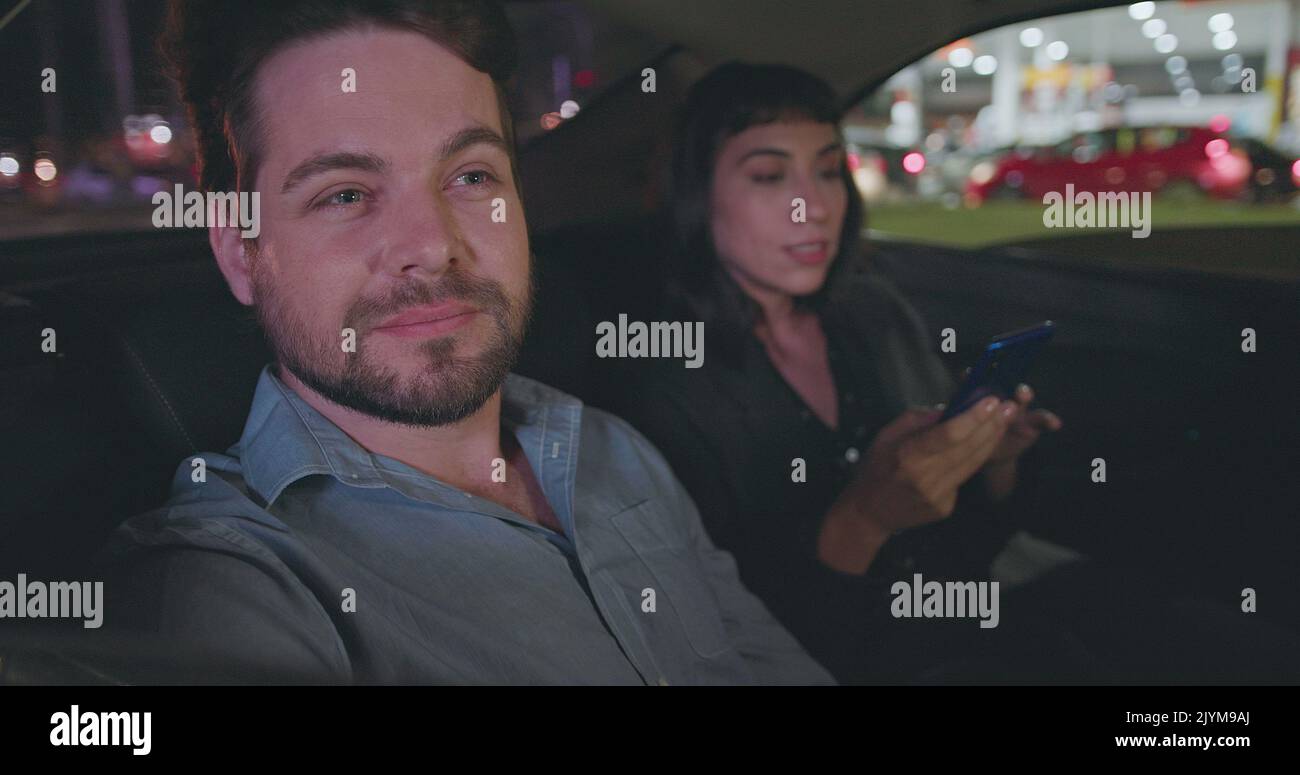 Young man and woman riding taxi in backseat after work at night. Male ...