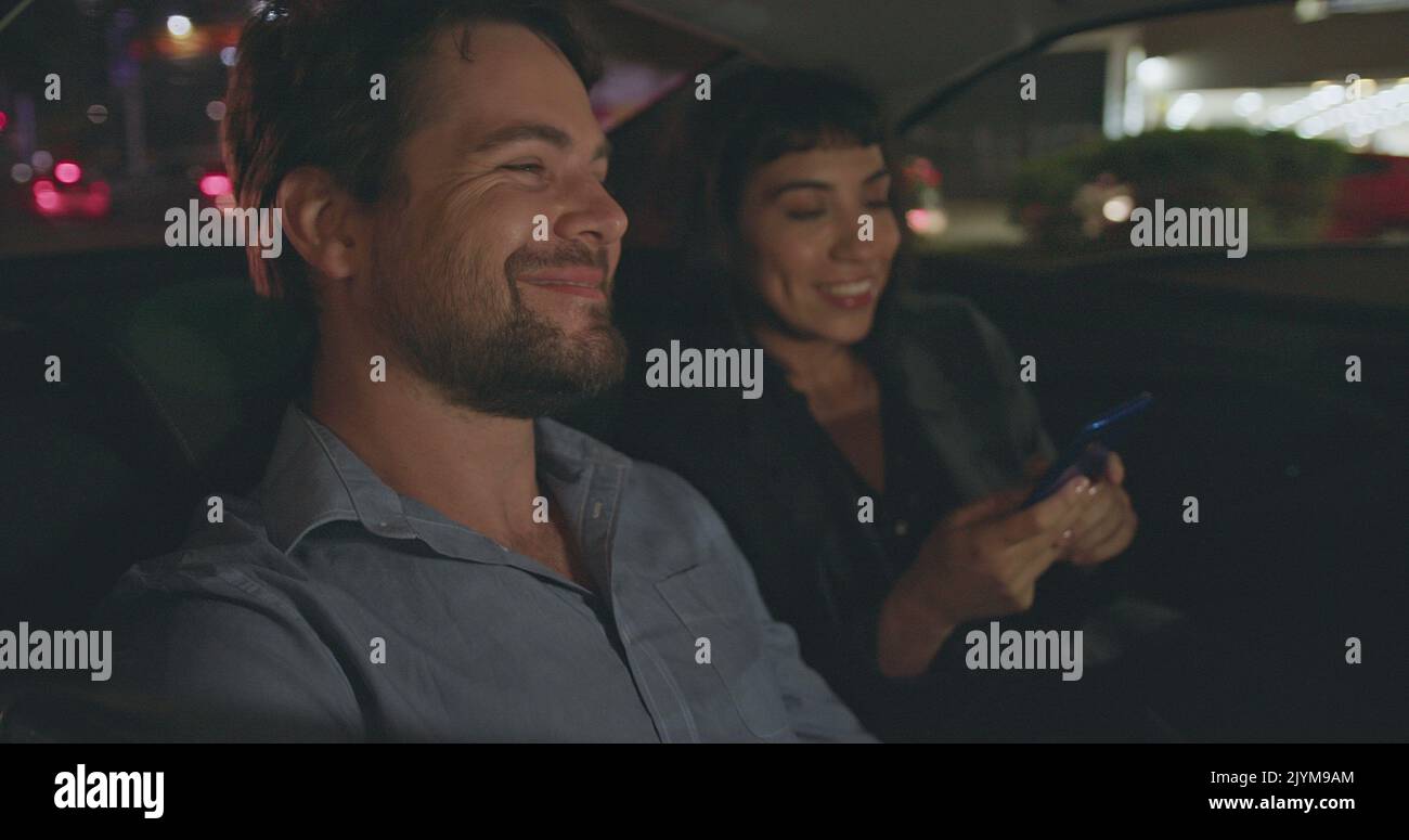 Young man and woman riding taxi in backseat after work at night. Male ...