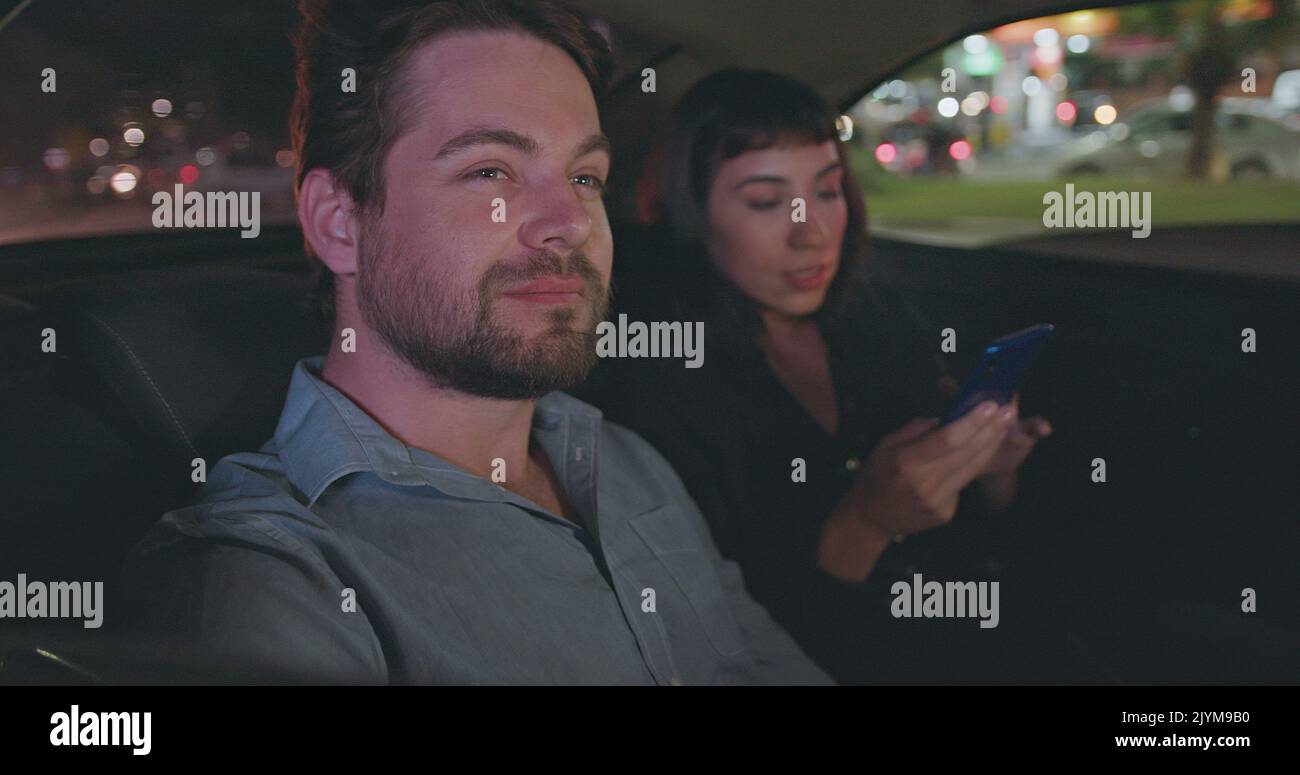 Young man and woman riding taxi in backseat after work at night. Male ...