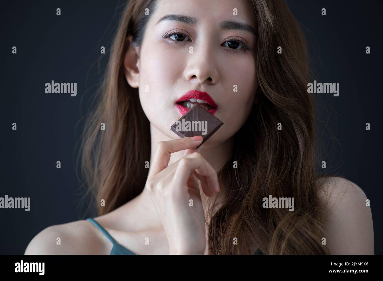 Beautiful young Chinese woman eating chocolate Stock Photo - Alamy